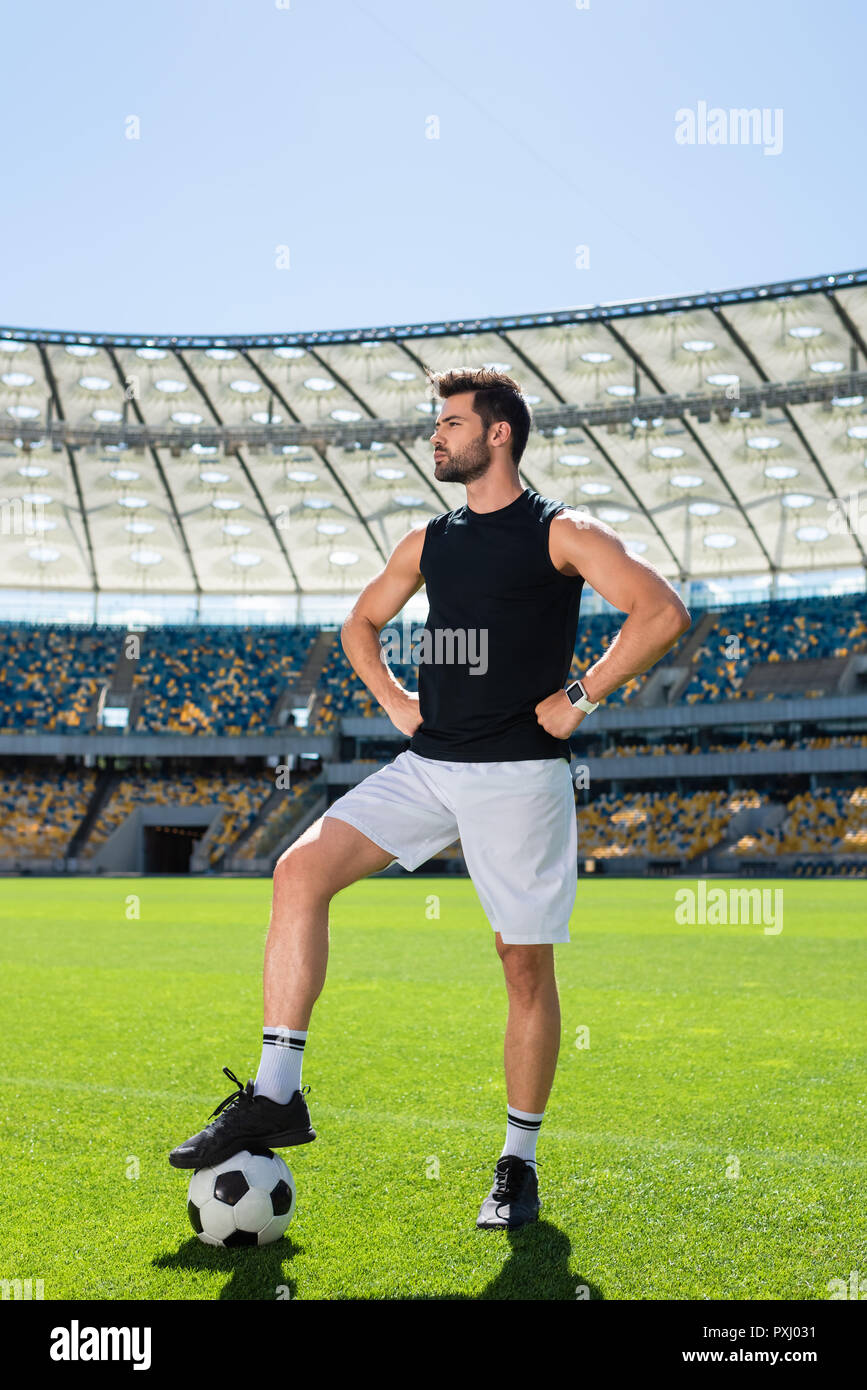 serious young soccer player standing at sports stadium with ball and ...