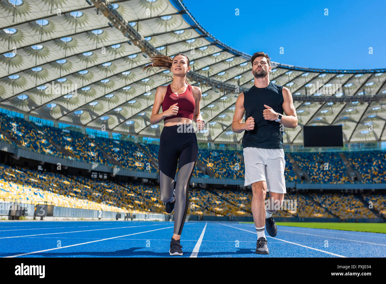 bottom view of young male and female joggers running on track at sports ...