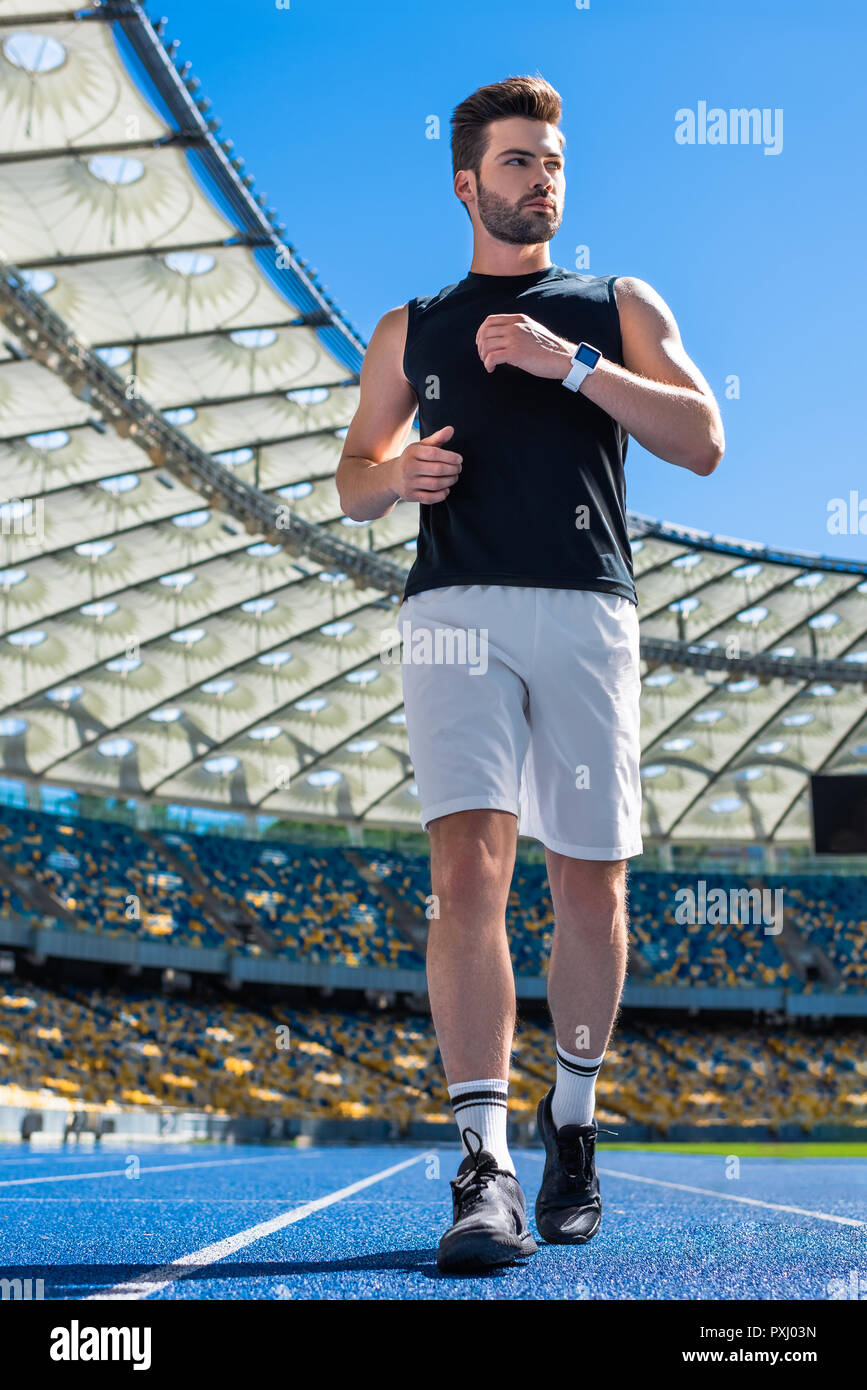 bottom view of fit young man exercising on running track at sports ...