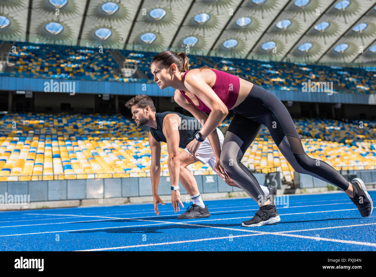 athletic young male and female sprinters in start position on running ...