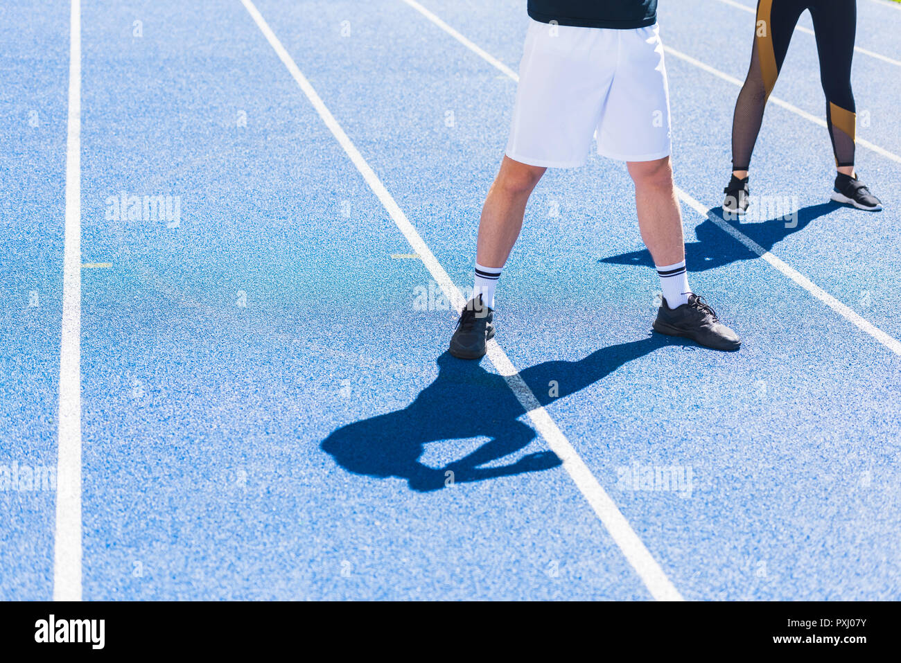 cropped shot of man and woman in modern sportswear standing on running ...