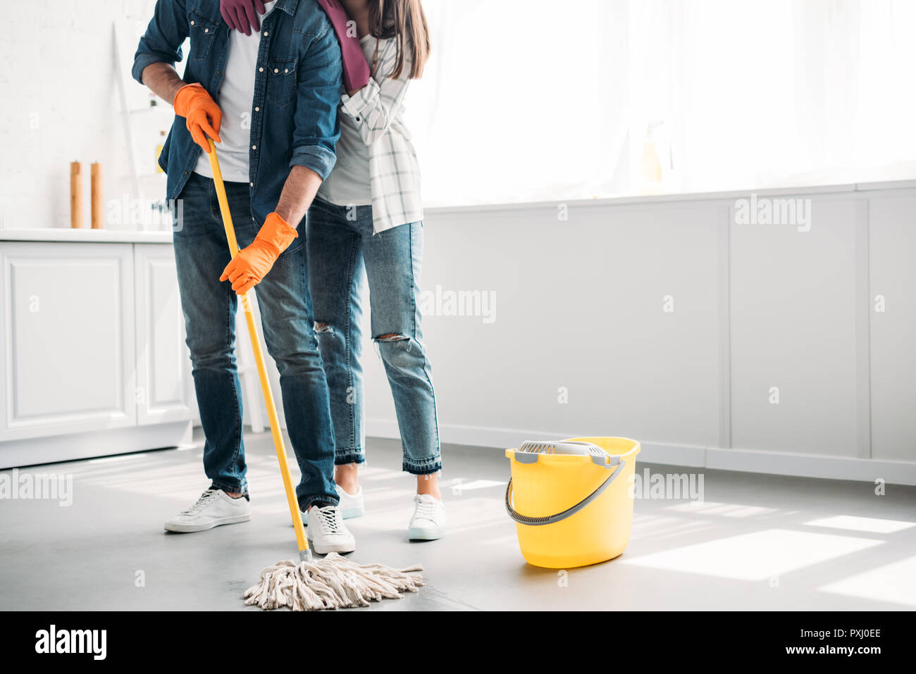 cropped image of boyfriend cleaning floor in kitchen with mop and ...