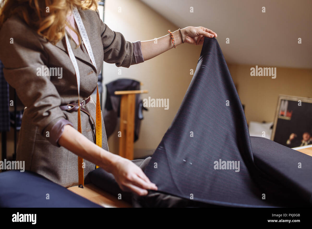 Female tailor choosing fabric for pattern cutting. Men's Wear industry ...