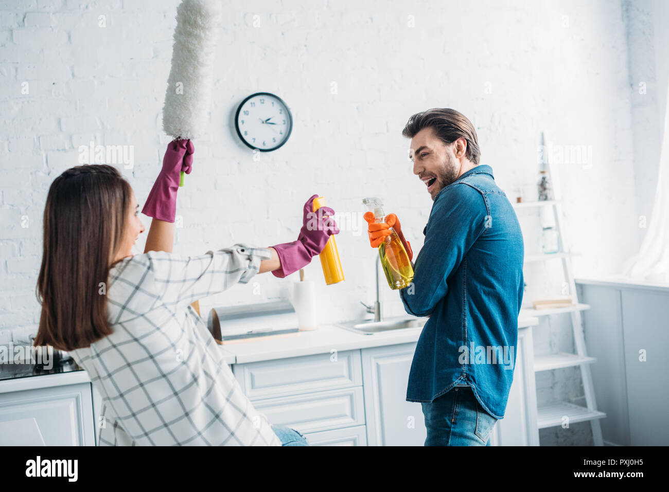 happy couple having fun during cleaning kitchen and fighting with ...
