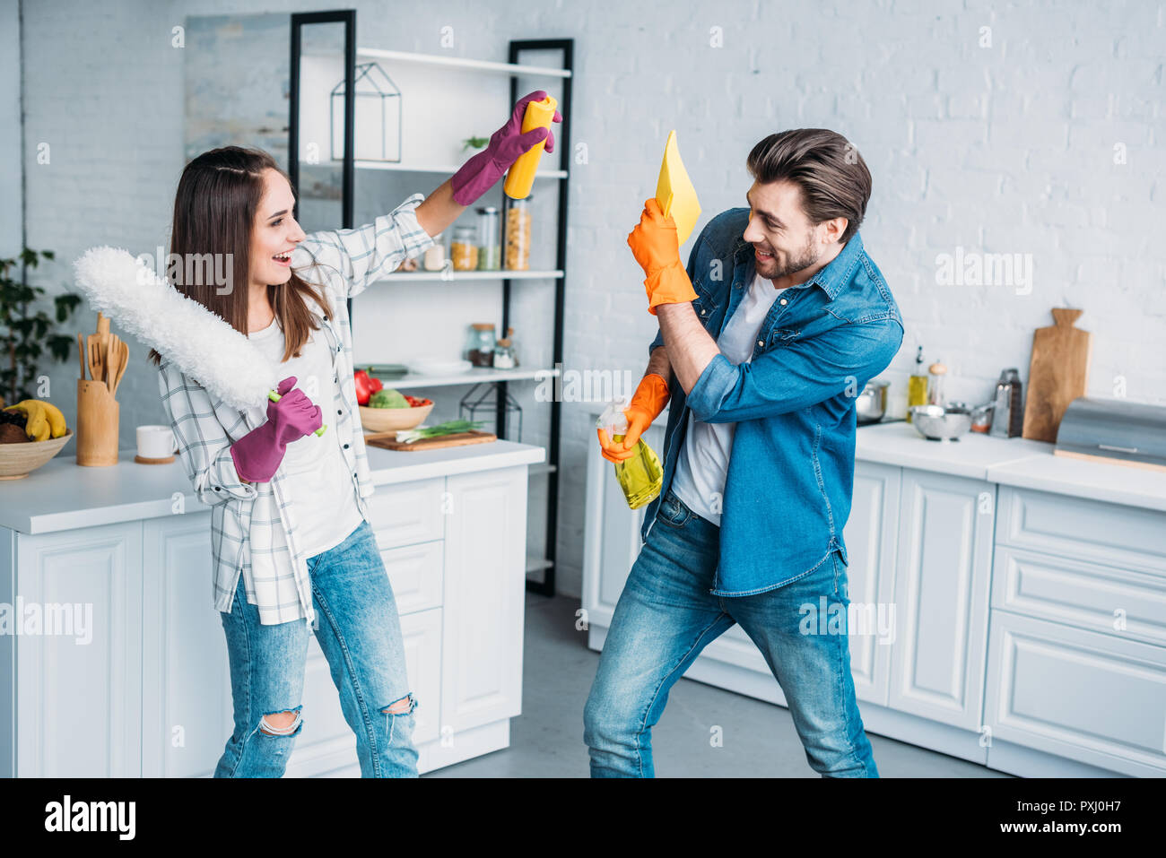 couple having fun during cleaning kitchen and fighting with cleaning ...