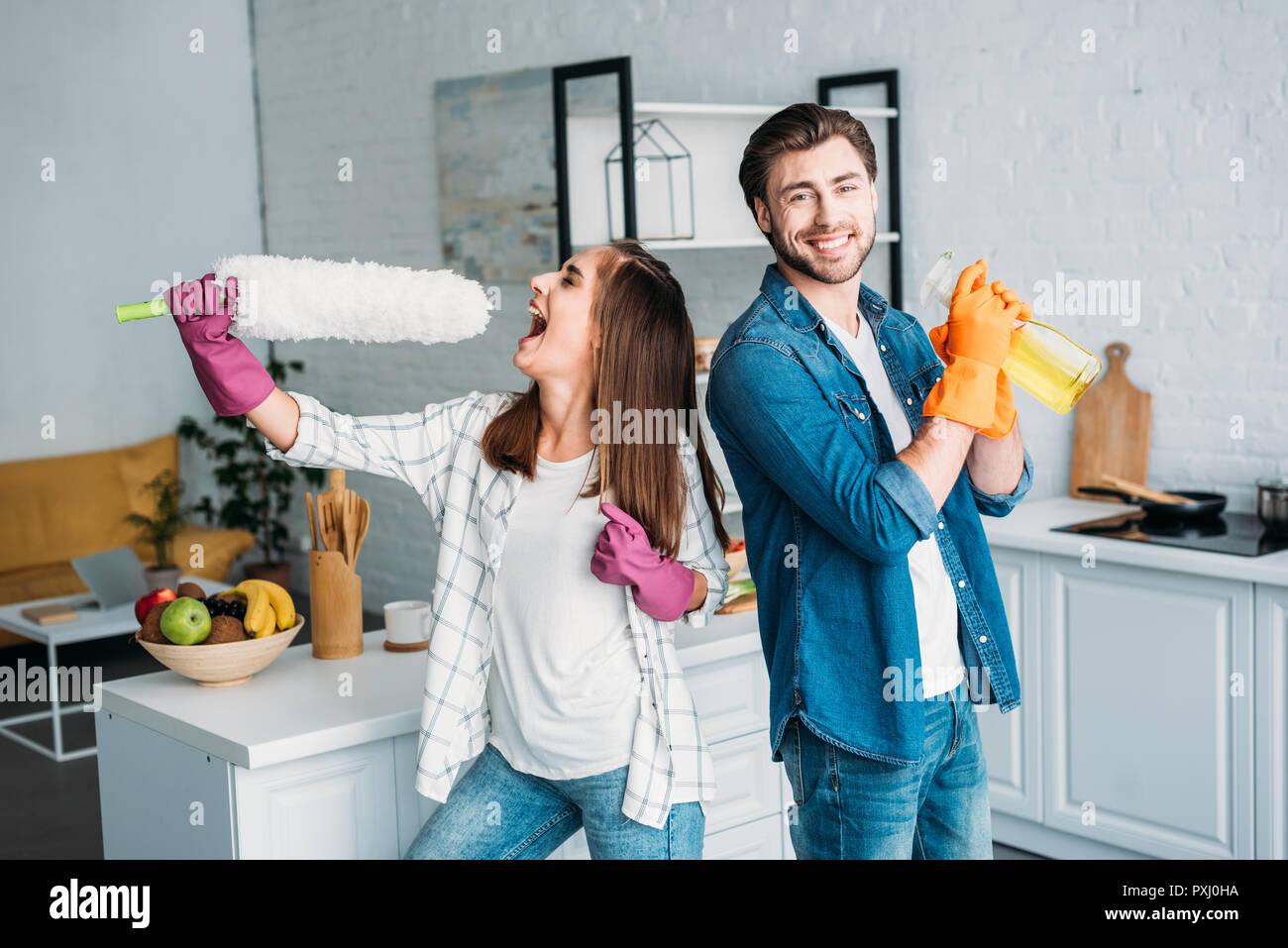 couple having fun during cleaning kitchen and girlfriend pretending ...