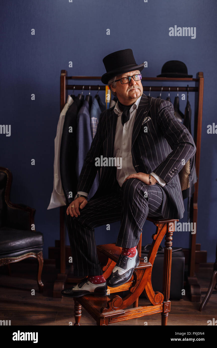 Confident retro style fashion man sitting on wooden stool tailor's ... Confident retro style fashion man sitting on wooden stool tailor's ...
