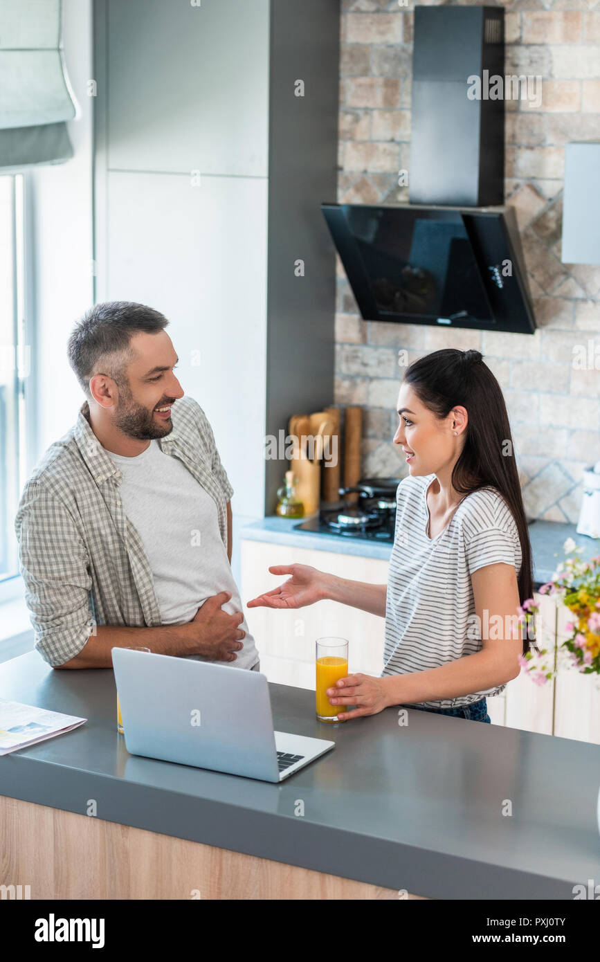 side view of couple with glasses of juice having conversation at ...