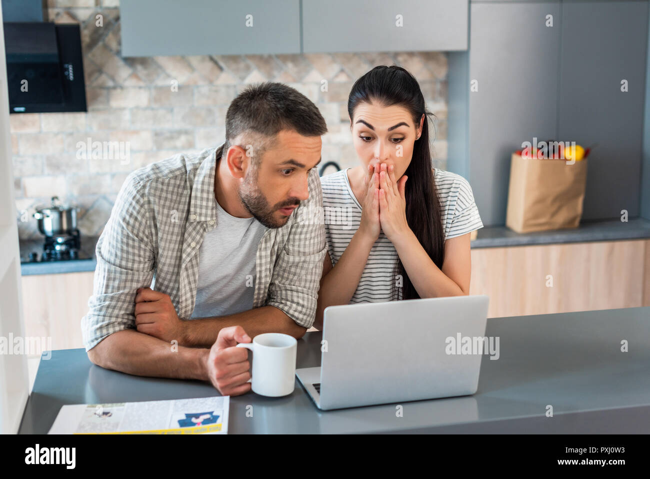 Portrait Of Shocked Married Couple Looking At Laptop Screen Together At