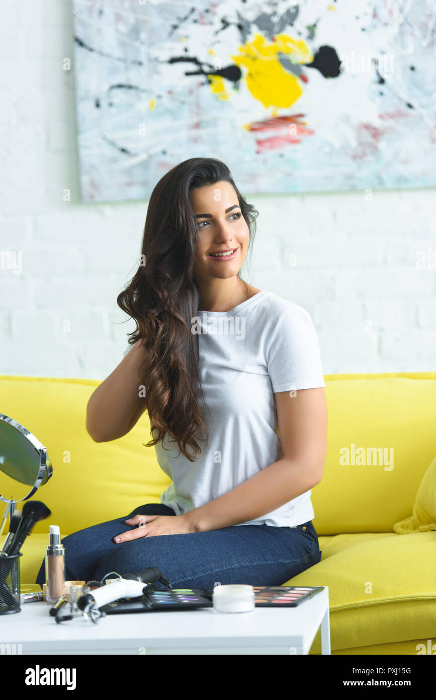beautiful smiling woman sitting on sofa at coffee table with mirror and ...