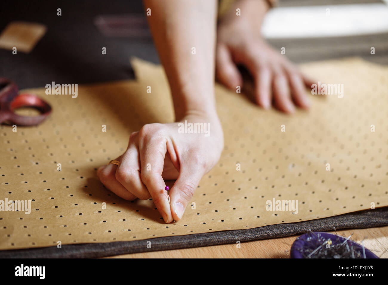 Tailor sticking a pin to cloth pattern at sewing workshop female Stock ...
