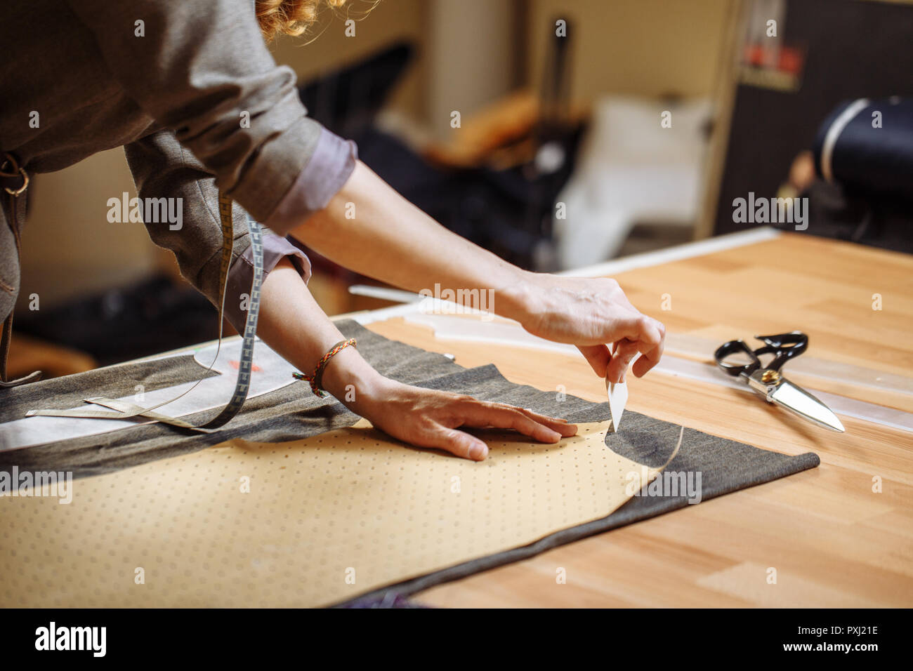 Professional adult female tailor marking cloth pattern with chalk at ...