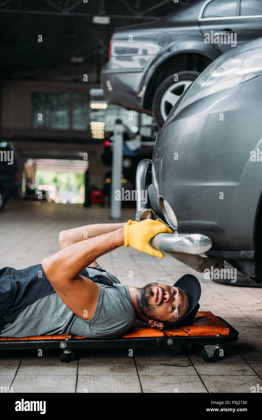 workman lying and working under car in mechanic shop Stock Photo - Alamy