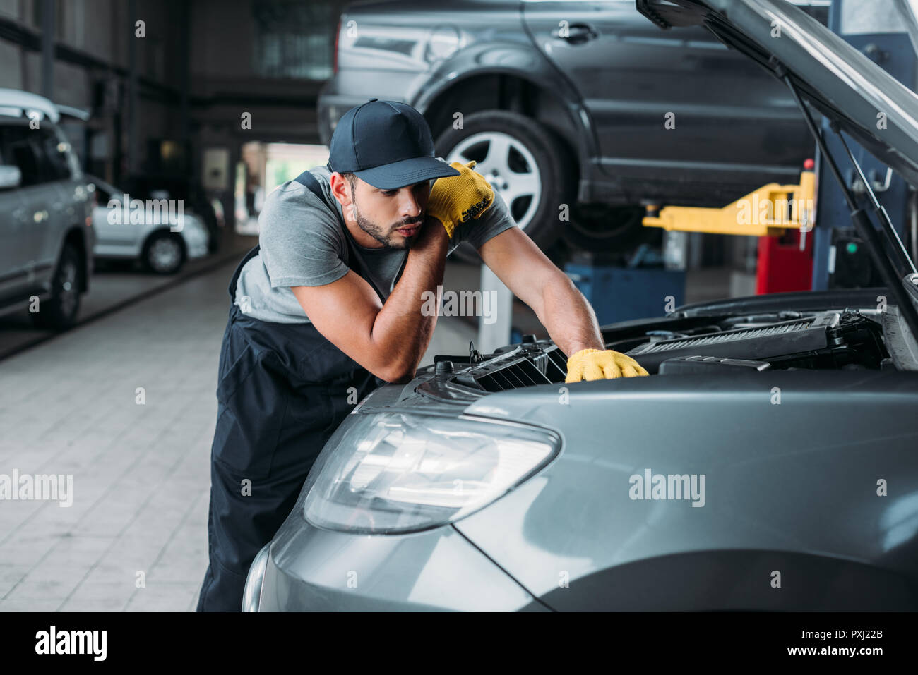 workman in uniform repairing car in mechanic shop Stock Photo - Alamy