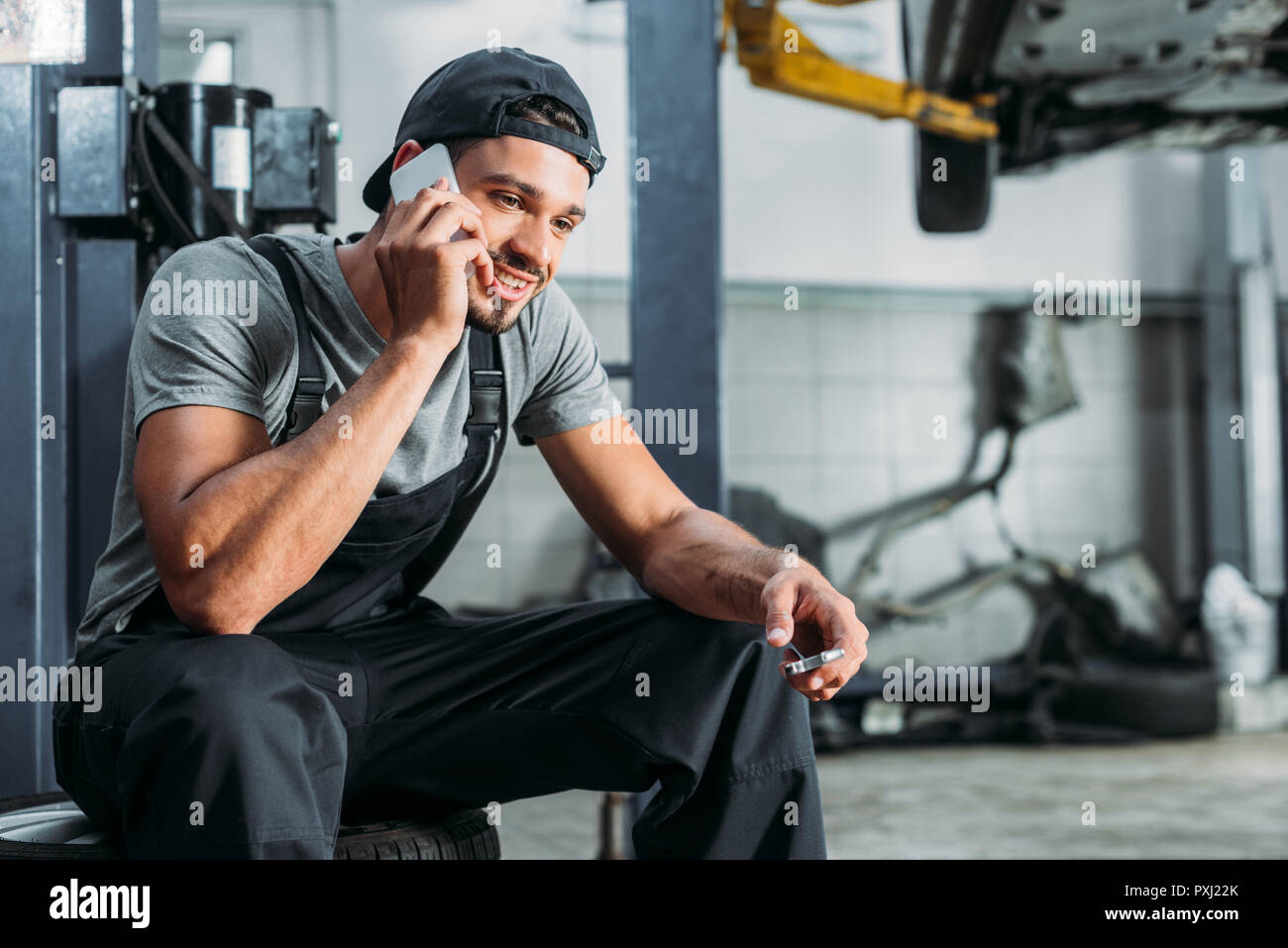 mechanic talking on smartphone and holding wrench in auto repair shop ...