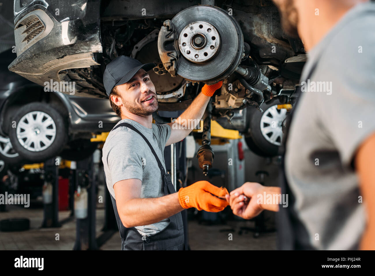 professional manual workers repairing car without wheel in mechanic ...