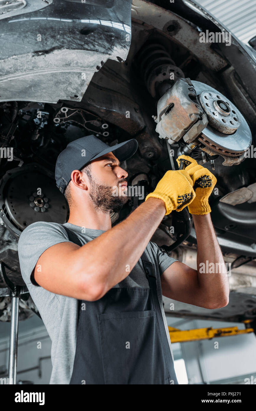 professional workman fixing car without wheel in mechanic shop Stock ...