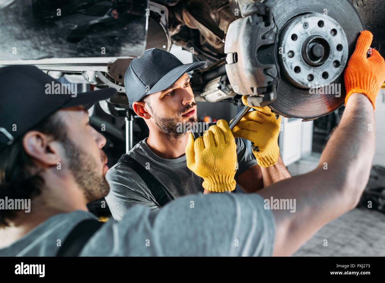 professional amle mechanics repairing car without wheel in auto repair ...