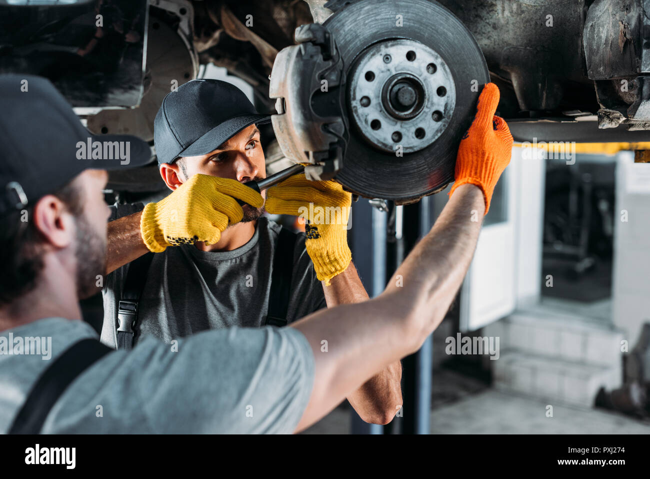 professional engineers repairing car without wheel in mechanic shop ...