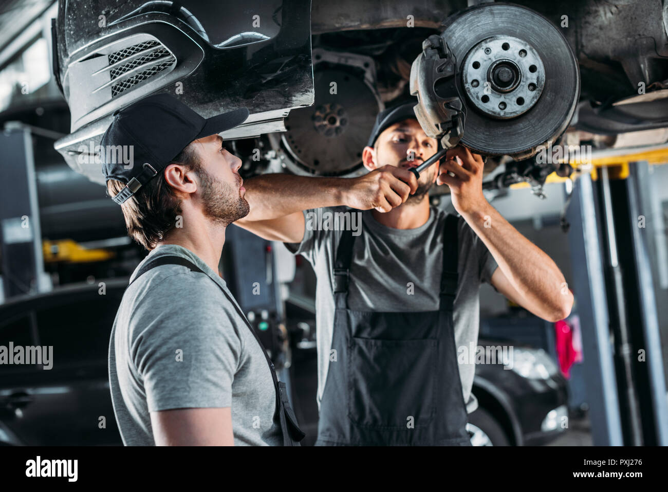 professional mechanics repairing car without wheel in auto repair shop ...