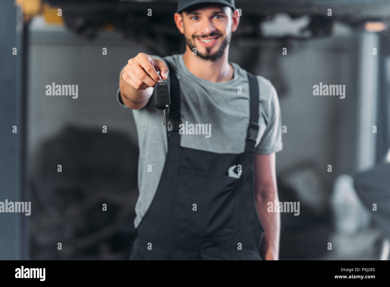smiling mechanic holding car key in auto repair shop Stock Photo - Alamy