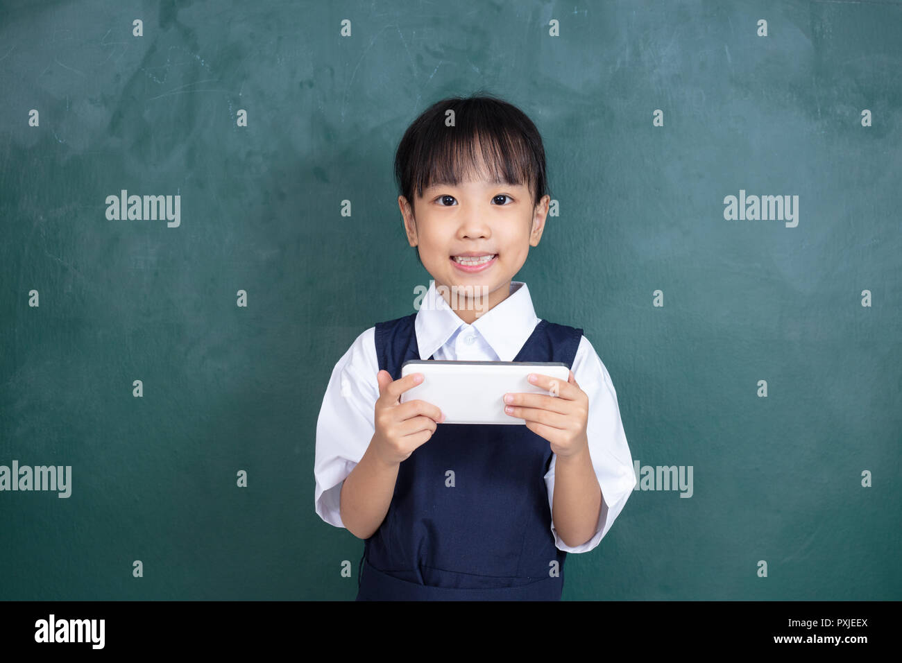 Asian Chinese little Girl in uniform playing digital tablet against ...