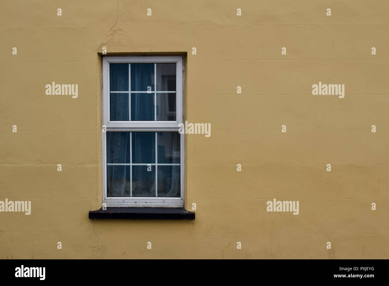 Close up view of a single white double-hung window on a smoothed yellow ...