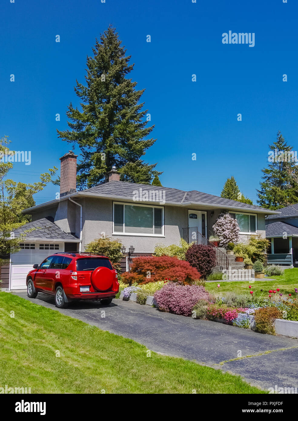 Modest residential house with car parked on asphalt driveway. Family ...