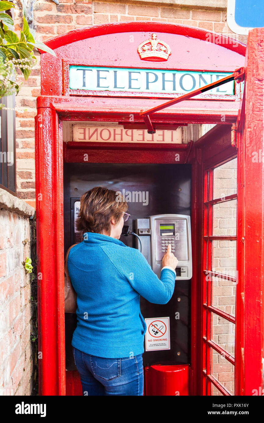 Woman chatting talking using a telephone in an traditional red English ...