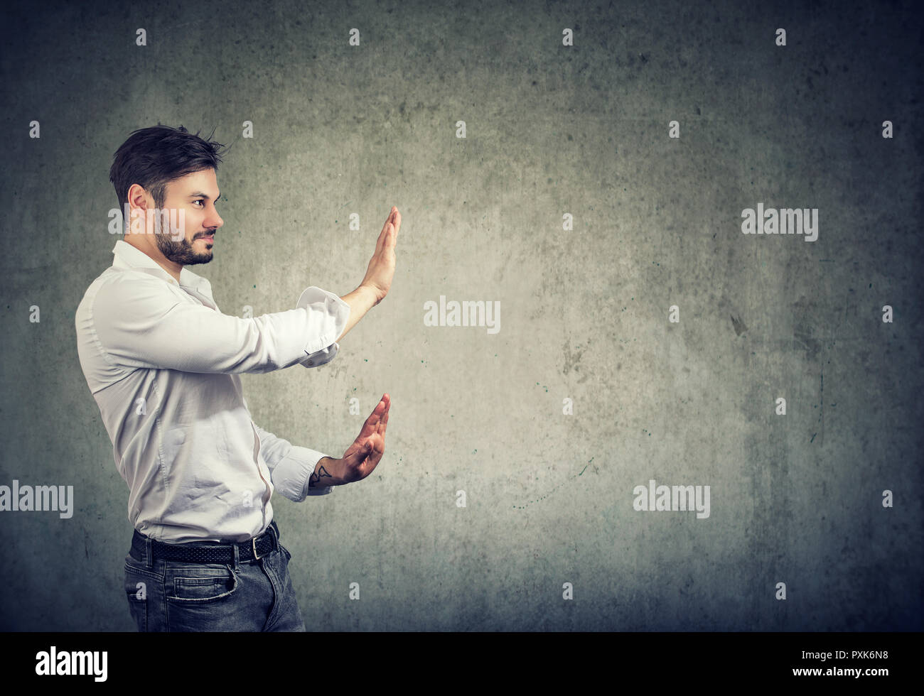 Side view of handsome modern man in white shirt holding hands in front ...