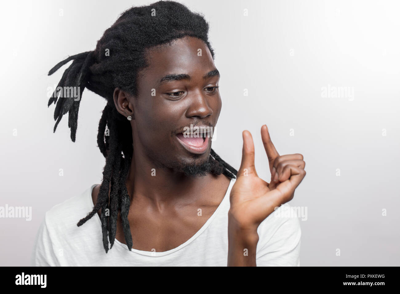 dark skinned man showing small thing while smiling and standing near ...