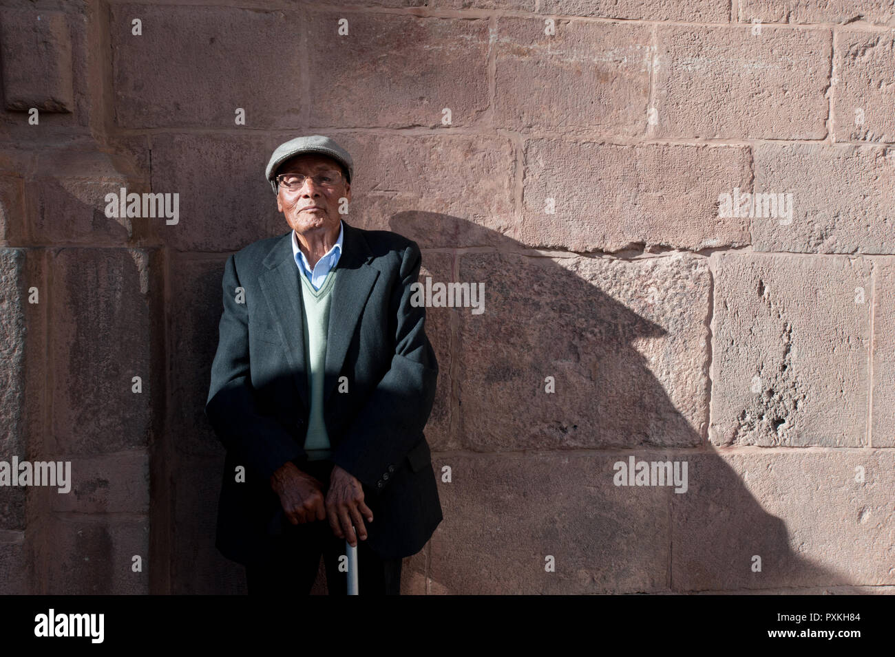Old Peruvian man, citizen of Cuzco, posing with an ancient Inca wall ...