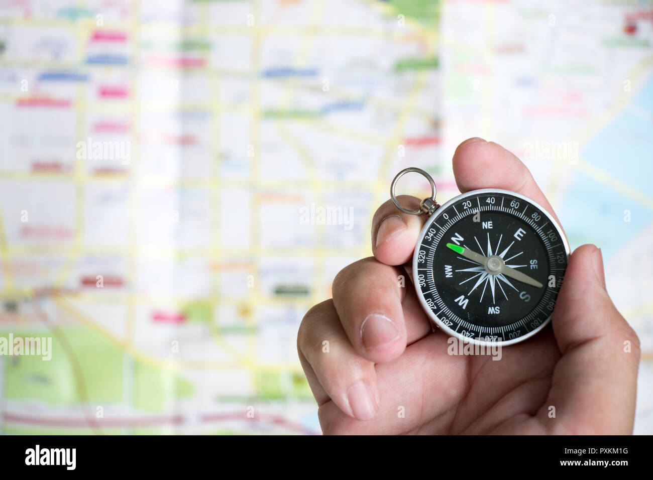 Man hold compass to check the direction with blurred map background ...