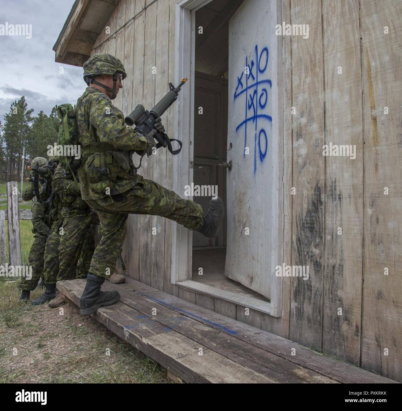 A Soldier of the 3rd Canadian Division, Canadian Army kicks a door open ...