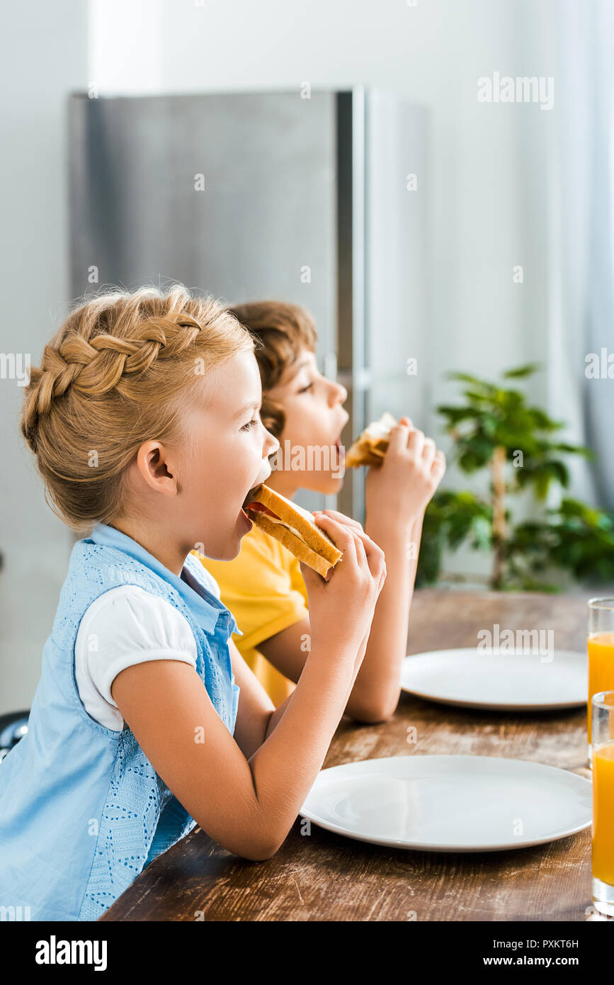 side view of cute little children eating tasty sandwiches Stock Photo ...