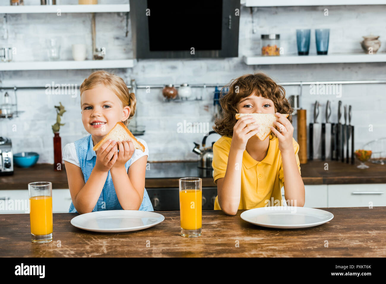 adorable happy kids eating tasty sandwiches and smiling at camera Stock ...