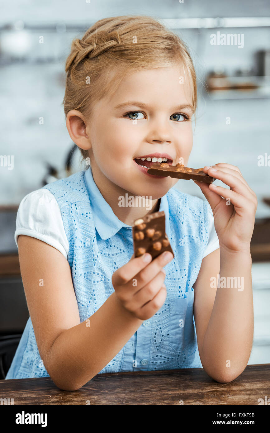 cute happy kid eating delicious chocolate with hazelnuts and smiling at ...