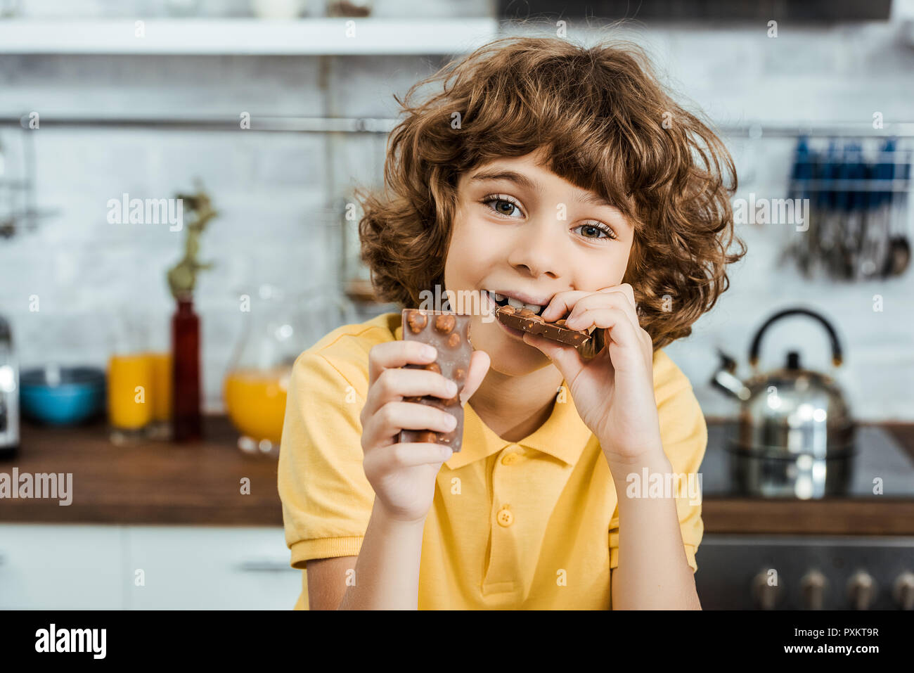 adorable happy boy eating chocolate with hazelnuts and looking at ...