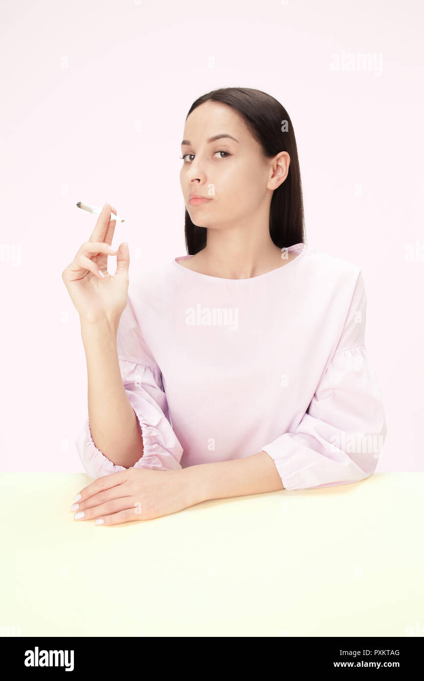 The young woman smoking cigarette while sitting at table at studio ...