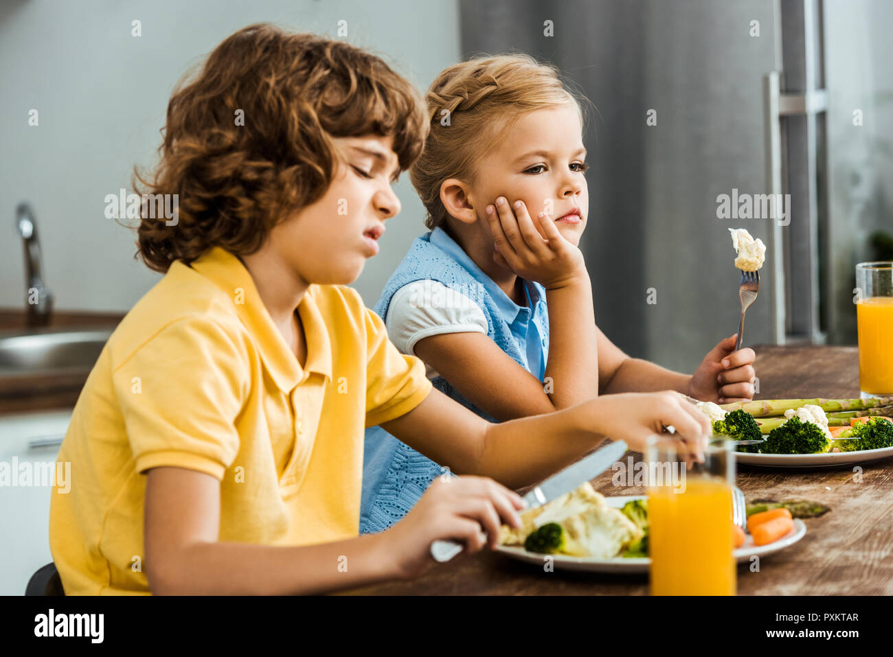 side view of unhappy little kids eating vegetables Stock Photo - Alamy