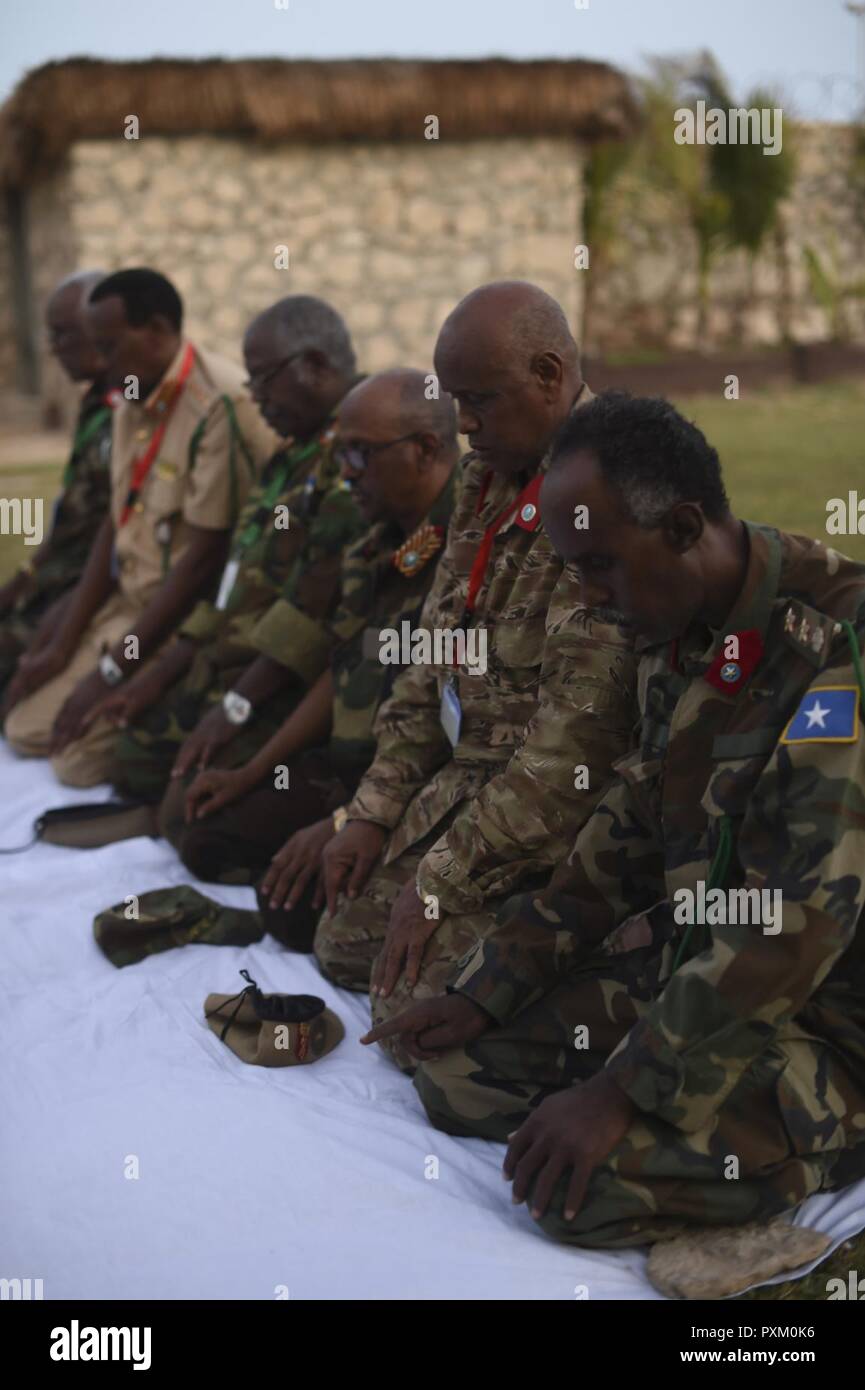 Members of the Somali National Army kneel to pray before an Iftar at ...