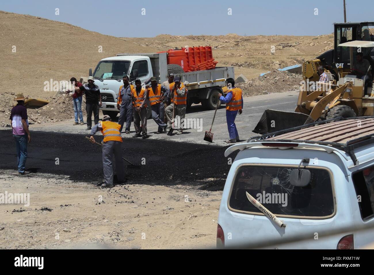 Iraqi citizens repair roads outside of west Mosul while Iraqi security ...