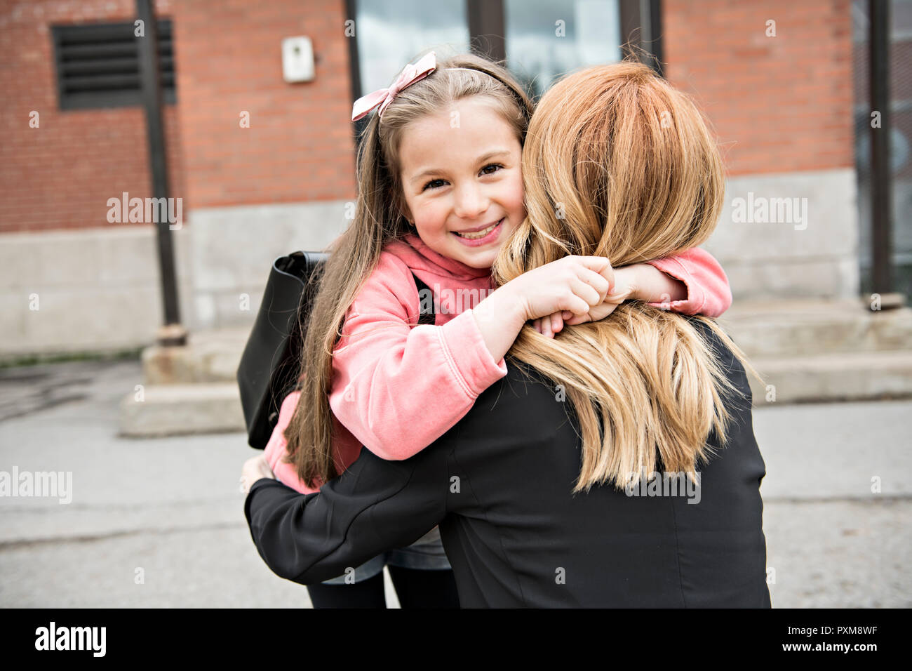 A girl and his mother hugging outside at school Stock Photo - Alamy