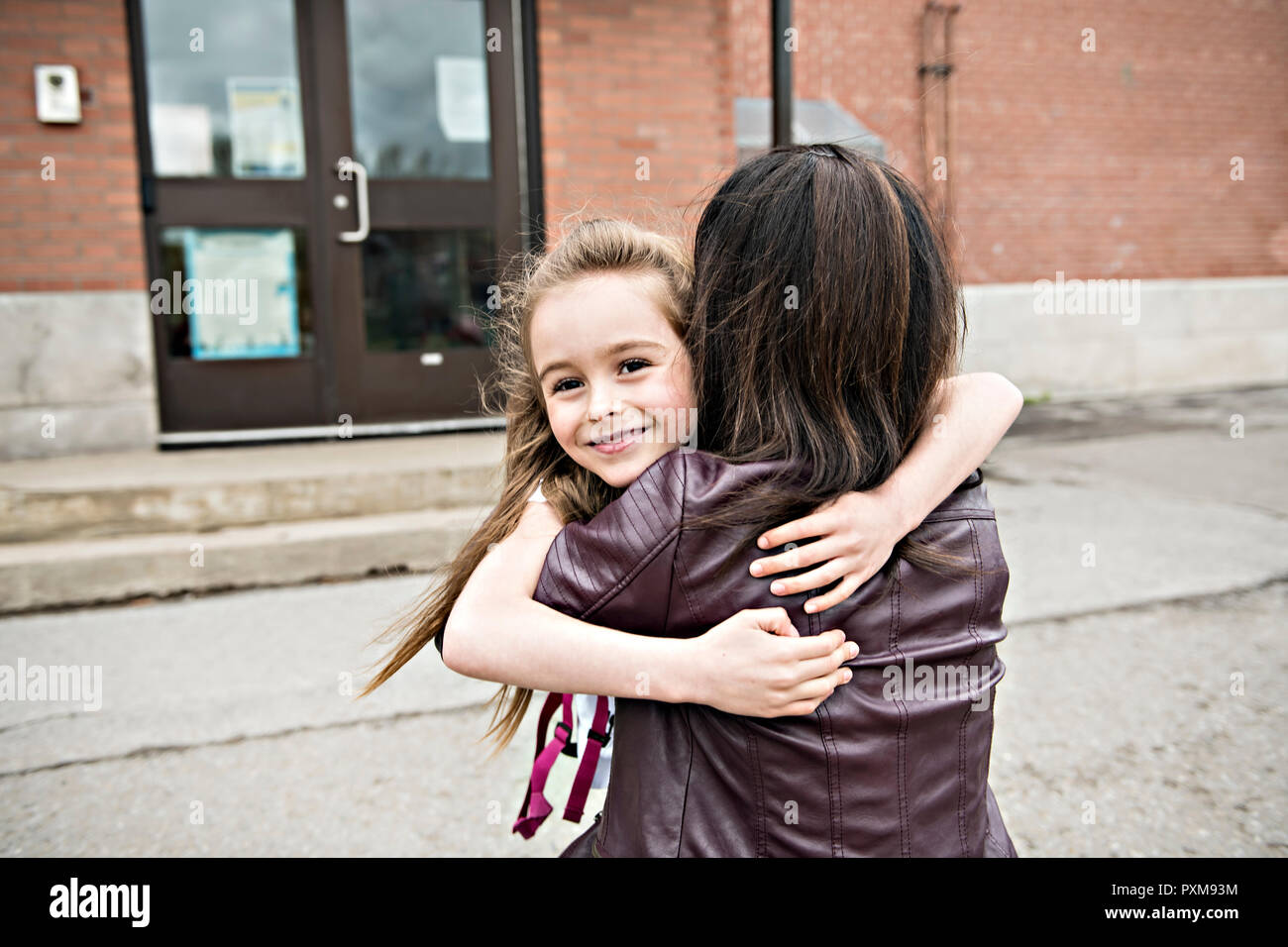 A girl and his mother hugging outside at school Stock Photo - Alamy