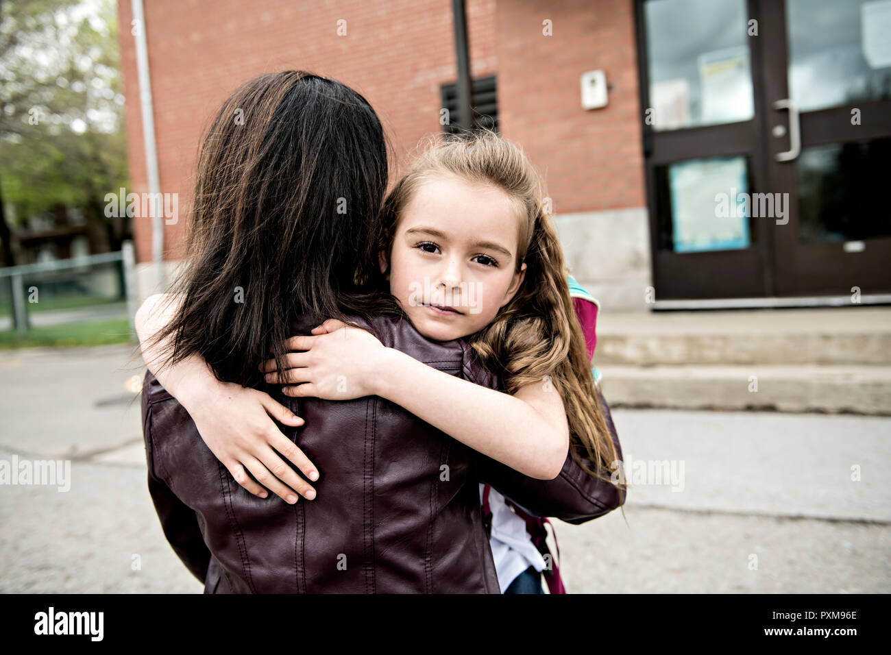 A girl and his mother hugging outside at school Stock Photo - Alamy