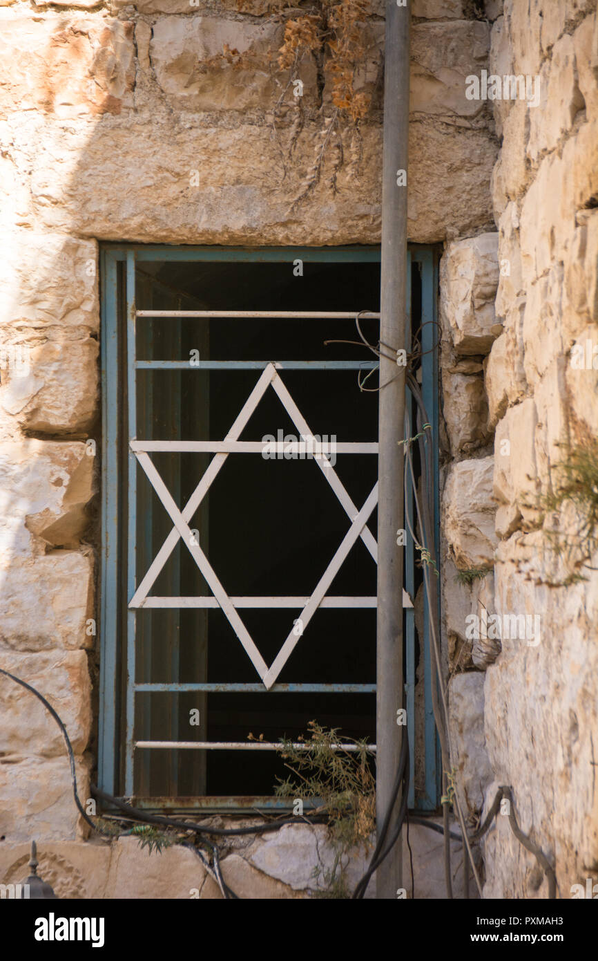 WIndow in an old stone wall with a Star of David shaped frame deisng ...