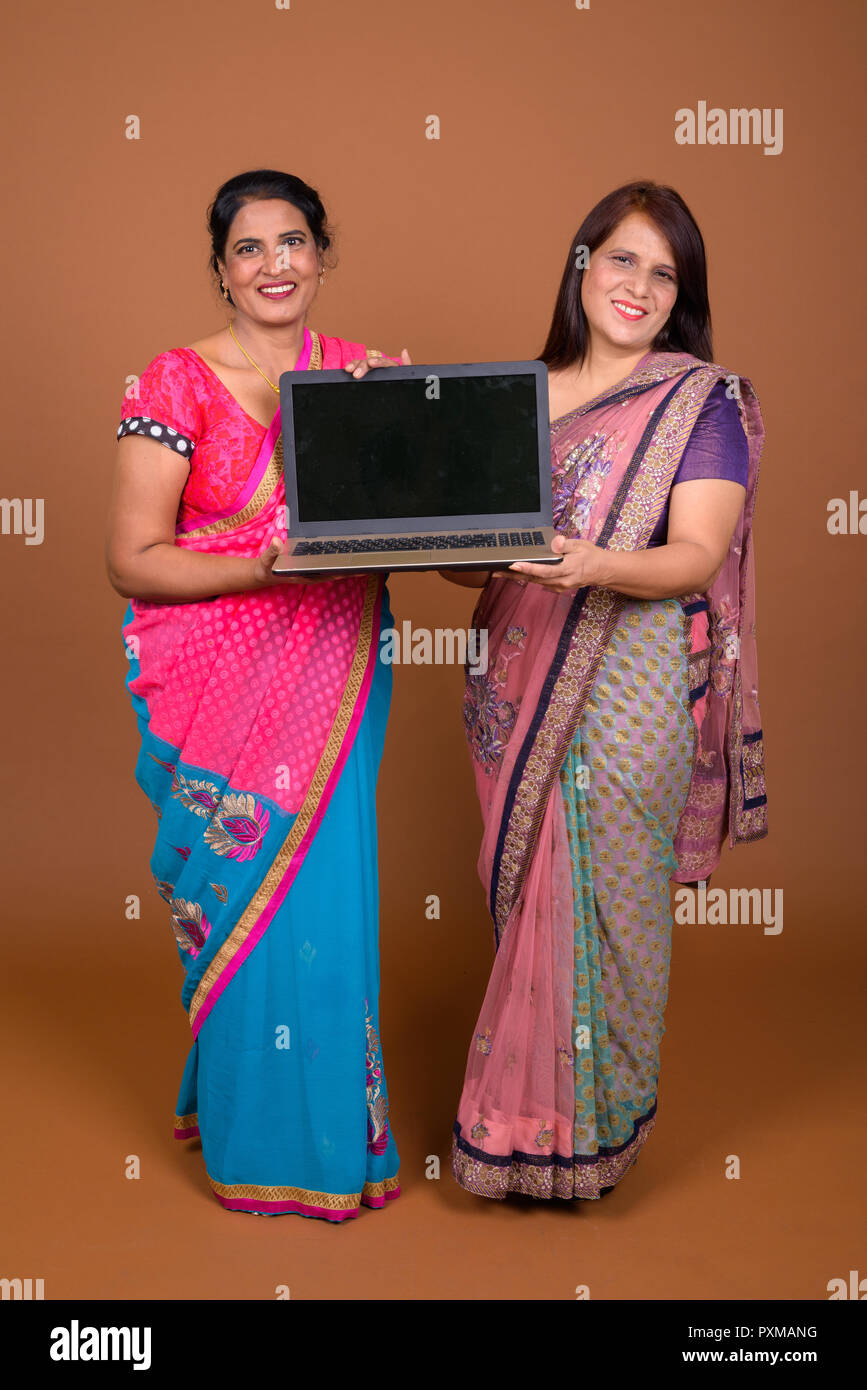 Two happy Indian women showing laptop computer with copy space Stock ...