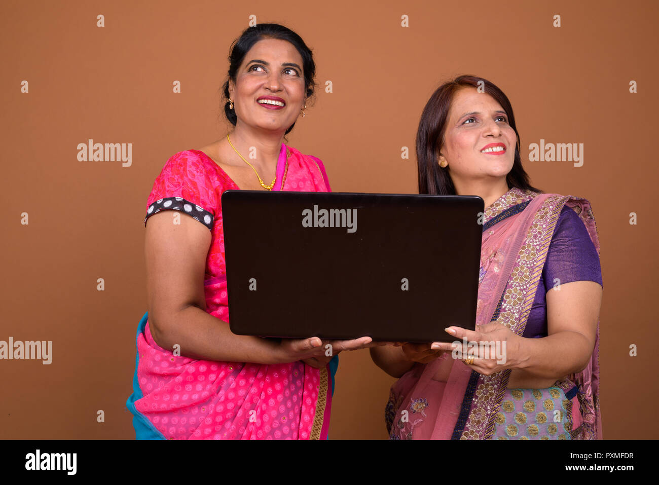 Two happy Indian woman using laptop computer and thinking Stock Photo ...