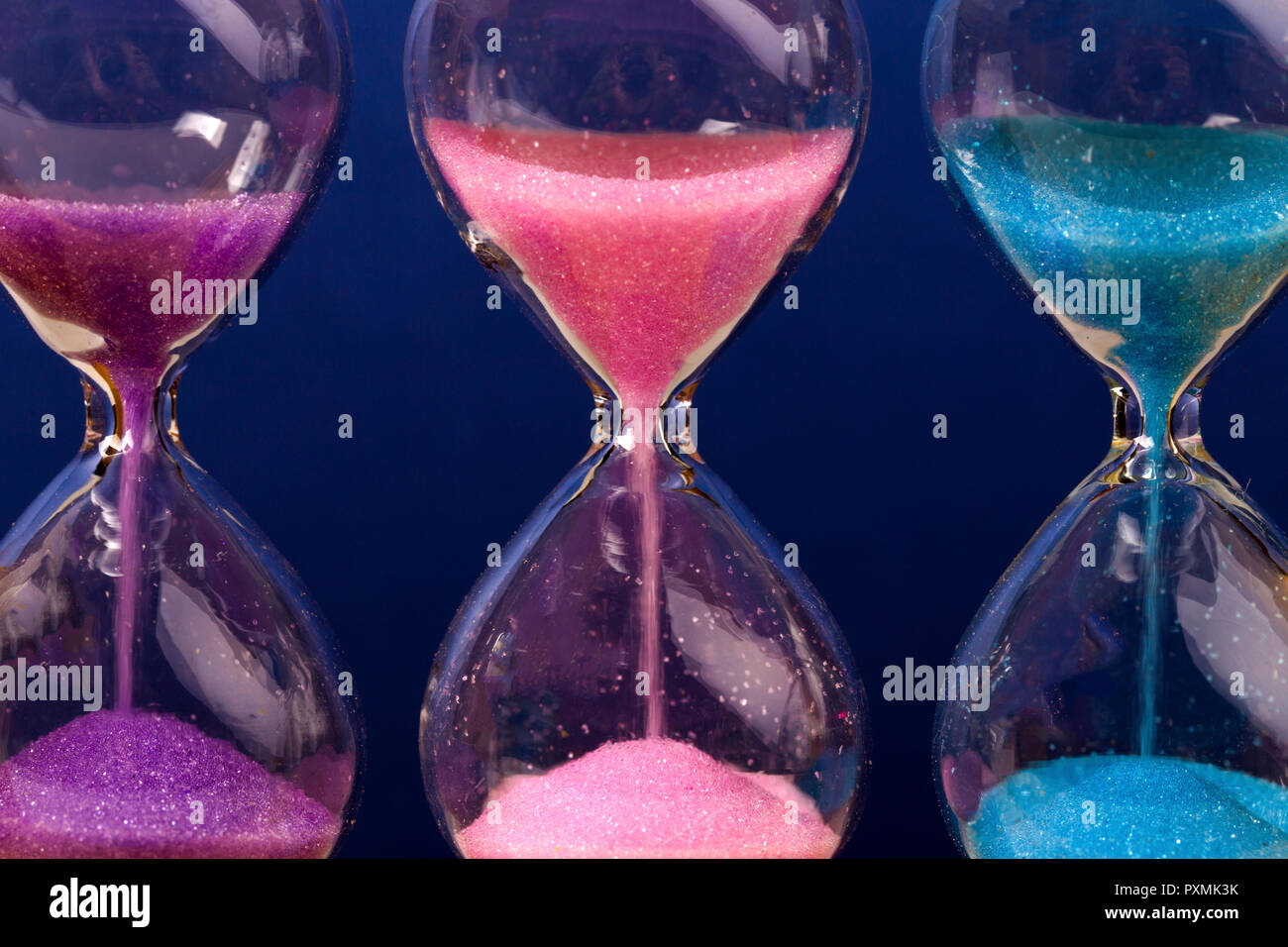 colored hourglass on a blue wall background Stock Photo - Alamy
