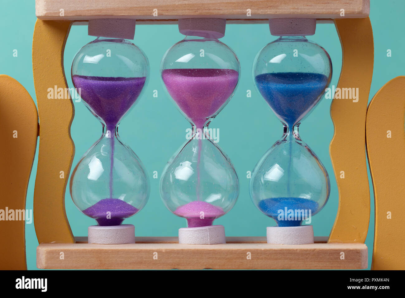 colored hourglass on the background of the azure wall Stock Photo - Alamy